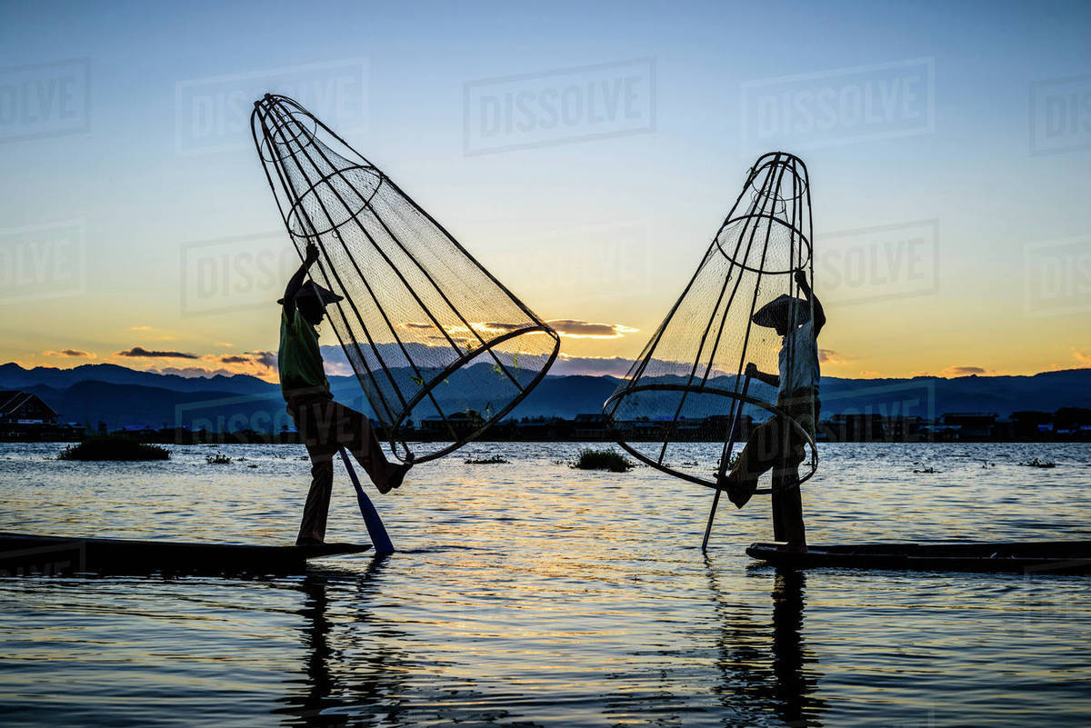 Asian fishermen using fishing nets in canoe on river - Royalty-free ...