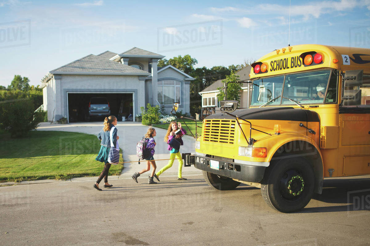 Caucasian girls walking to school bus - Stock Photo - Dissolve