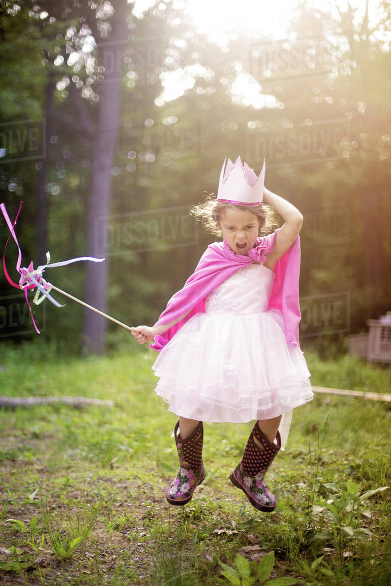 Girl playing princess in backyard - Stock Photo - Dissolve