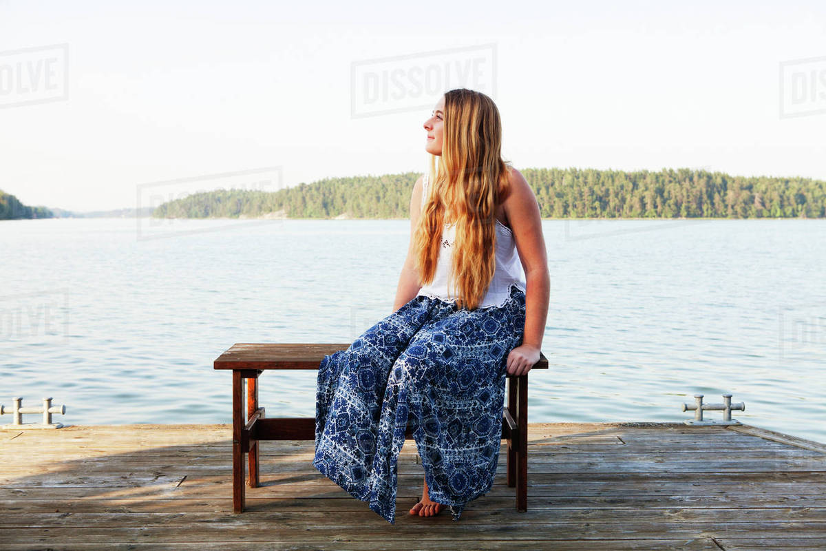 Caucasian teenage girl sitting on wooden dock at lake - Stock Photo ...