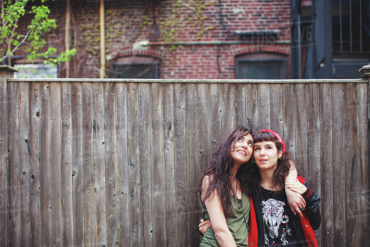 Friends hugging at wooden fence - Stock Photo - Dissolve