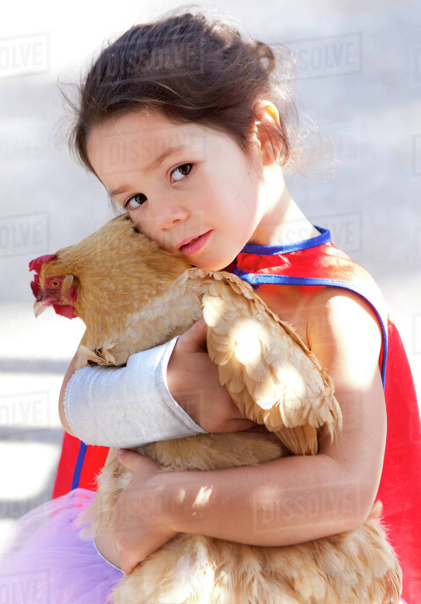 Mixed race girl hugging chicken - Stock Photo - Dissolve