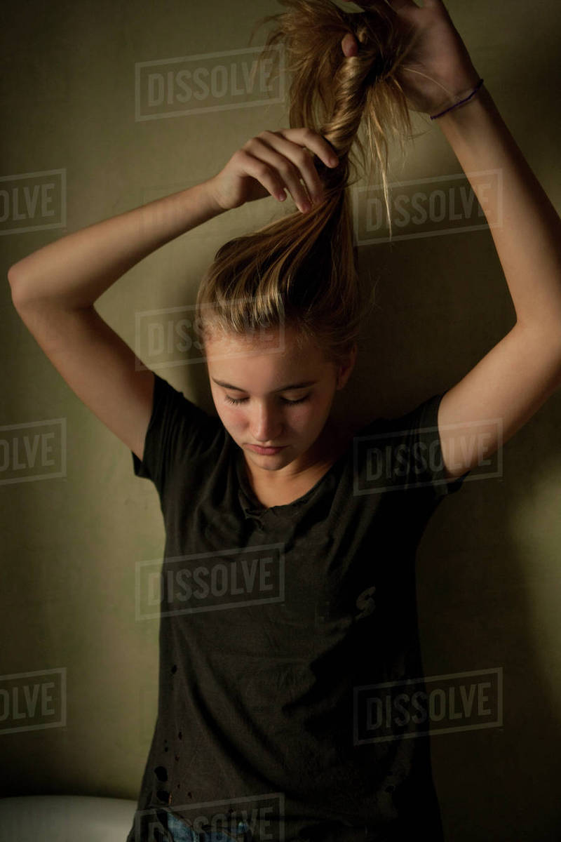 Serious teenage girl twisting her hair - Stock Photo - Dissolve