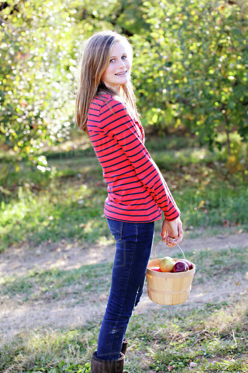 Caucasian girl picking fruit in orchard - Stock Photo - Dissolve