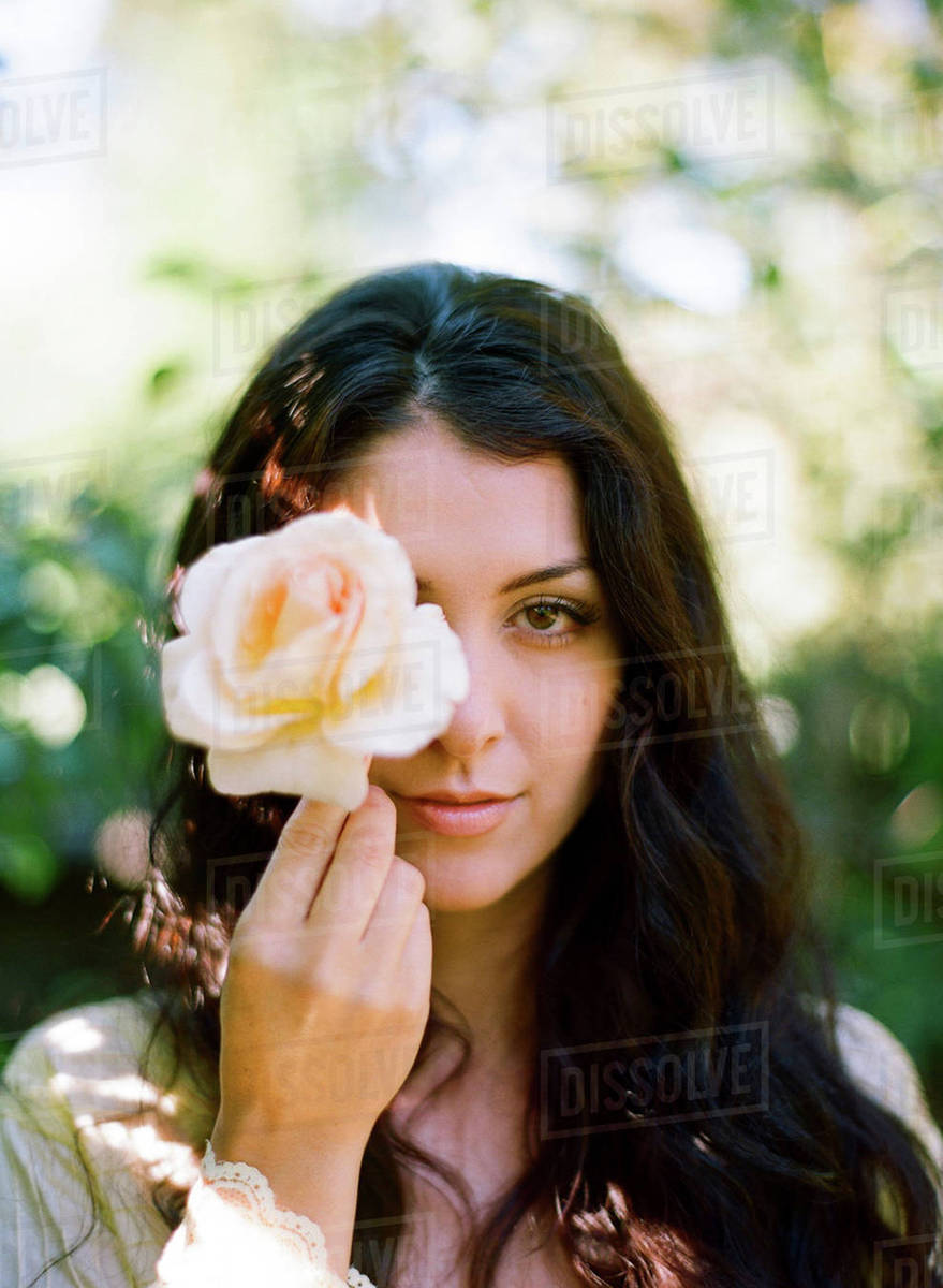 Close up of woman holding rose outdoors - Stock Photo - Dissolve