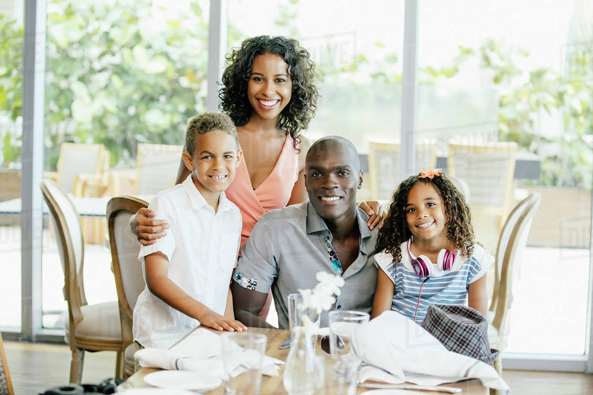 Family smiling at restaurant table - Royalty-free Stock Photo | Dissolve