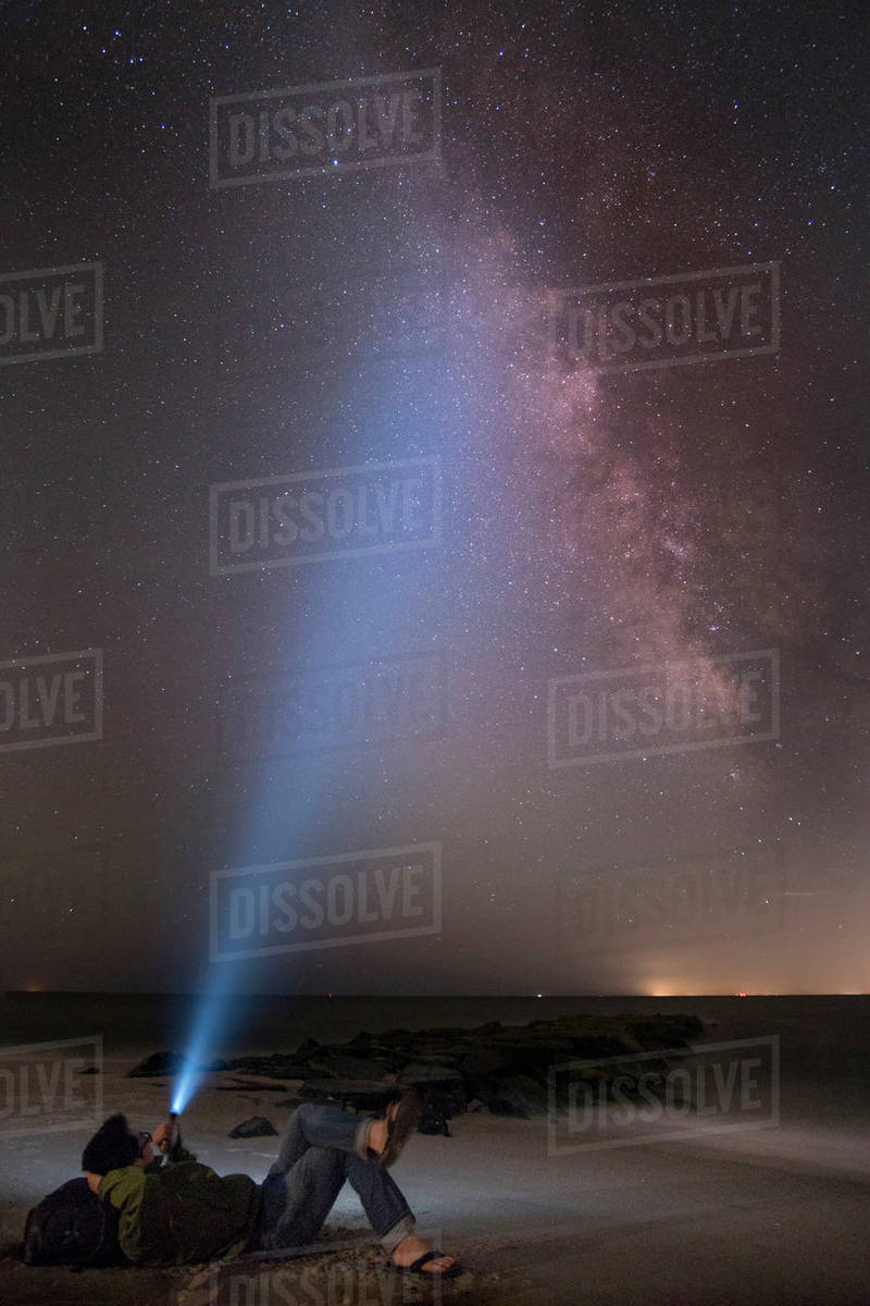 Asian man shining flashlight on starry sky - Royalty-free Stock Photo ...