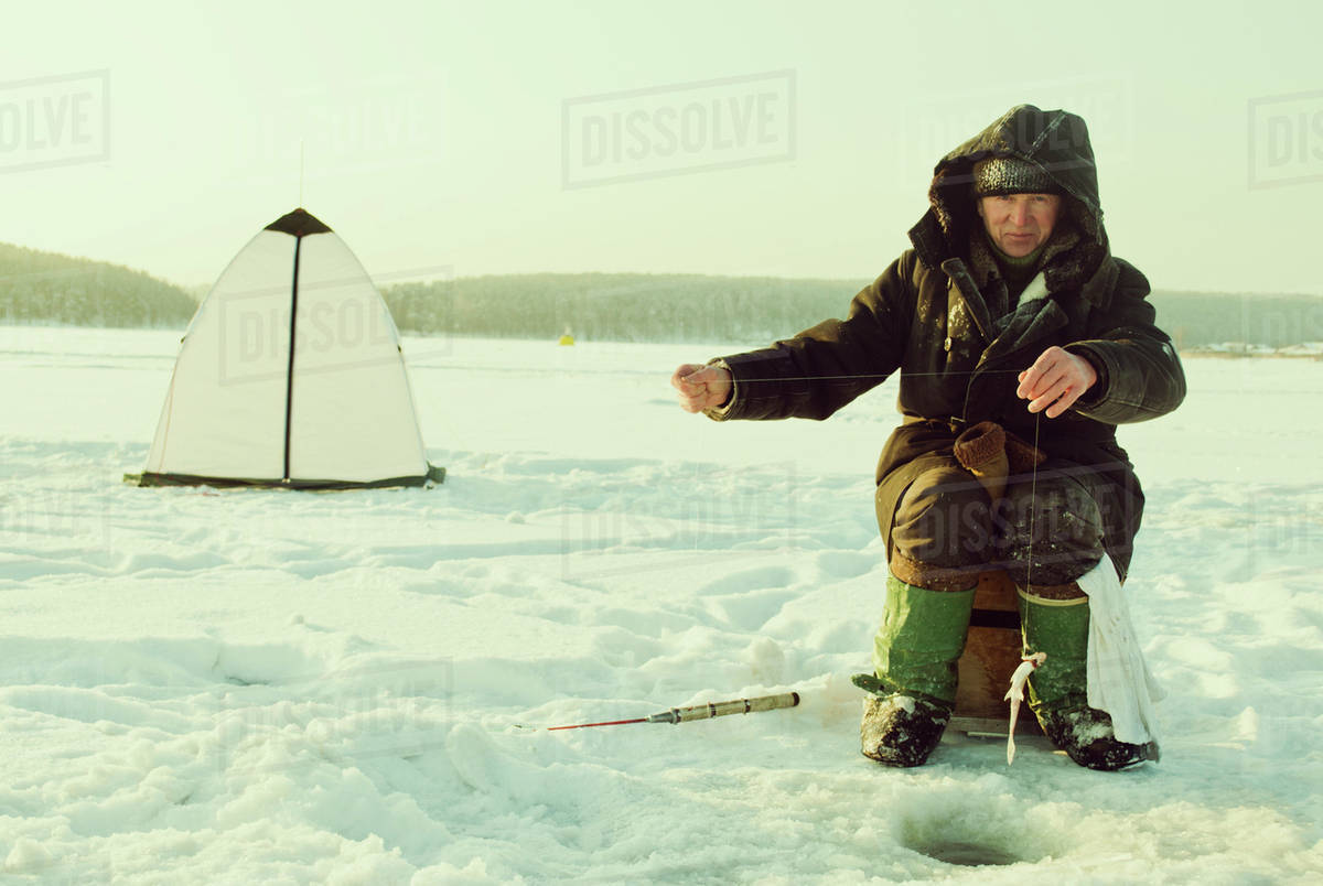 Caucasian man ice fishing on remote lake - Royalty-free Stock Photo ...