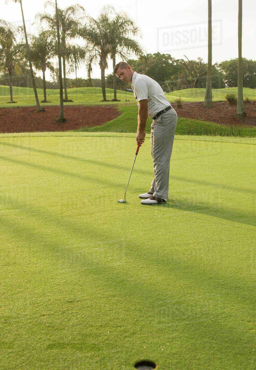 Caucasian man putting on golf course - Stock Photo - Dissolve