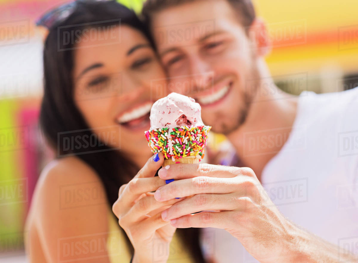Hispanic couple sharing ice cream cone outdoors - Royalty-free Stock ...