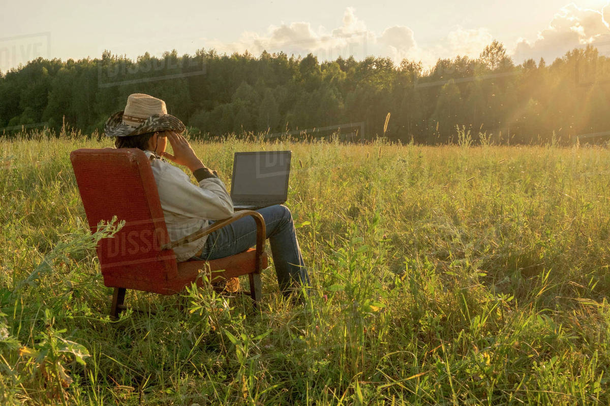 Mari man sitting on chair in field using laptop - Royalty-free Stock ...
