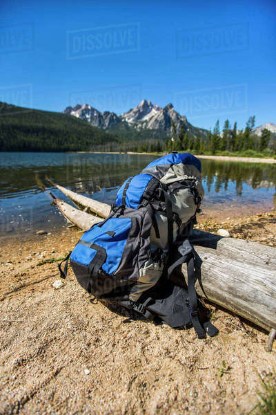Backpack leaning on log near river - Royalty-free Stock Photo | Dissolve