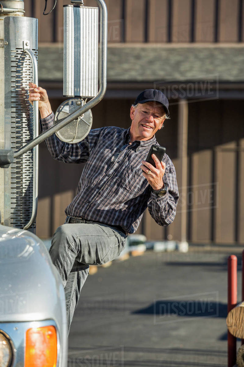 Caucasian man climbing into semi-truck texting on cell phone - Royalty ...