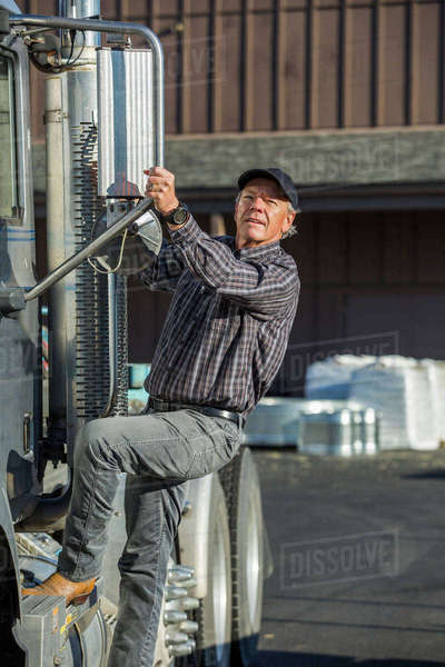 Caucasian man climbing into semi-truck - Royalty-free Stock Photo ...