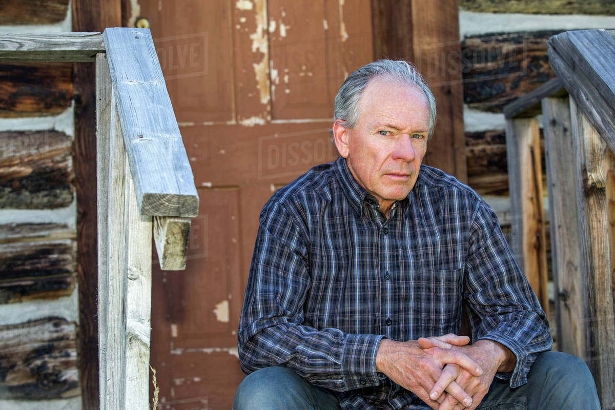 Serious Caucasian man sitting on wooden front stoop - Royalty-free ...