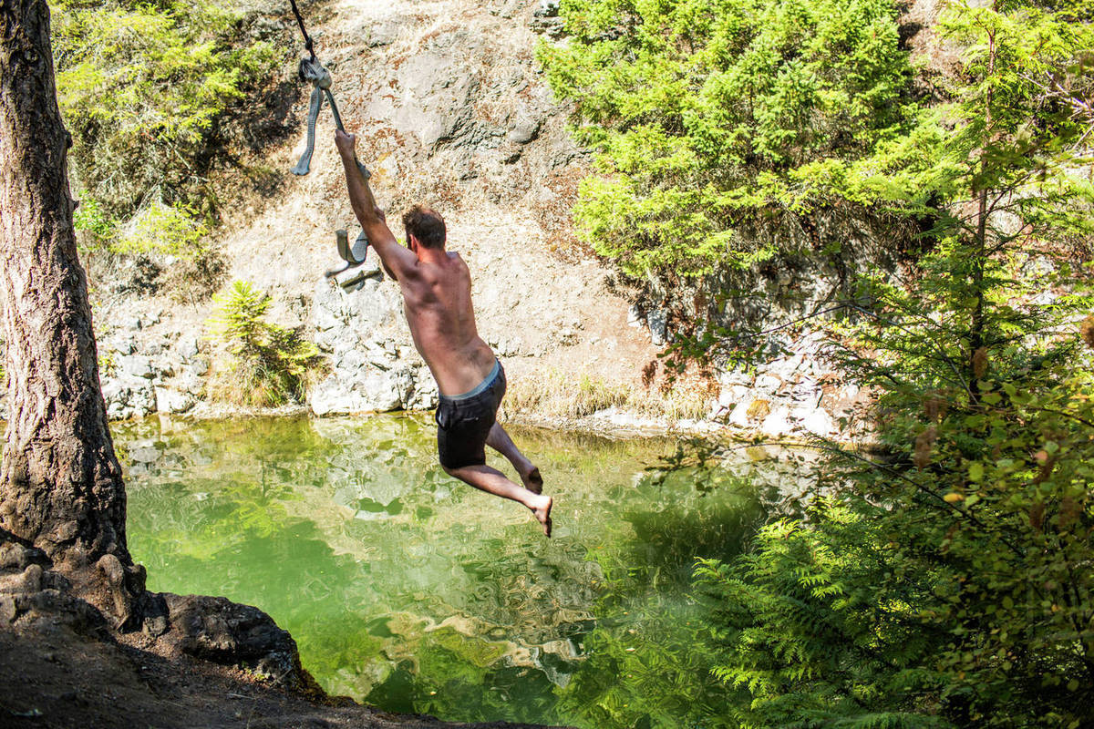 Caucasian man swinging on rope over water - Royalty-free Stock Photo ...