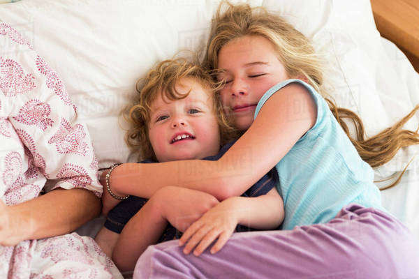 Caucasian brother and sister cuddling on bed - Royalty-free Stock Photo ...