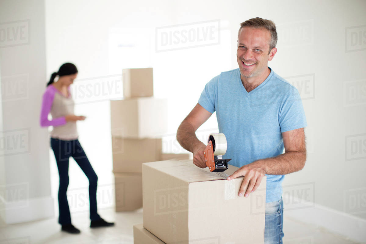 Man taping cardboard box to move - Royalty-free Stock Photo | Dissolve