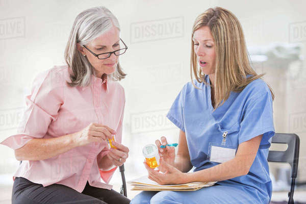Caucasian nurse explaining prescription to patient - Stock Photo - Dissolve