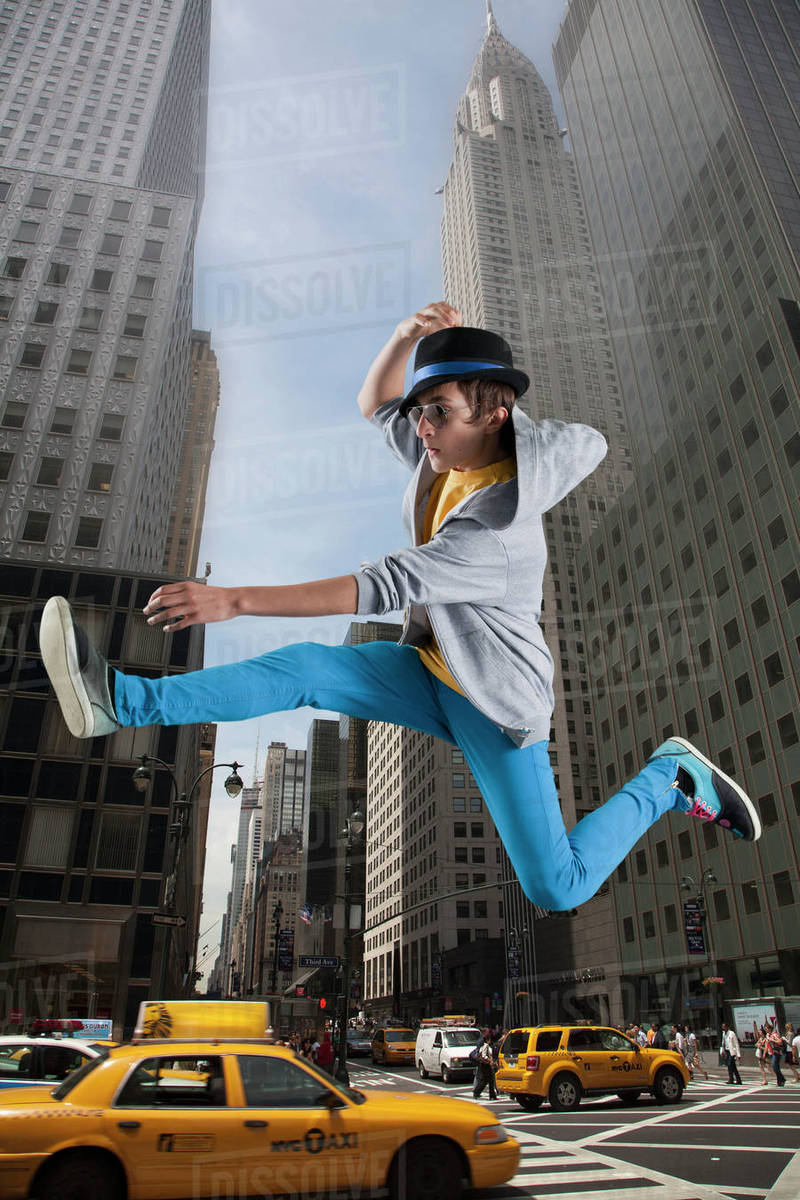 Caucasian man jumping over taxis in city - Stock Photo - Dissolve