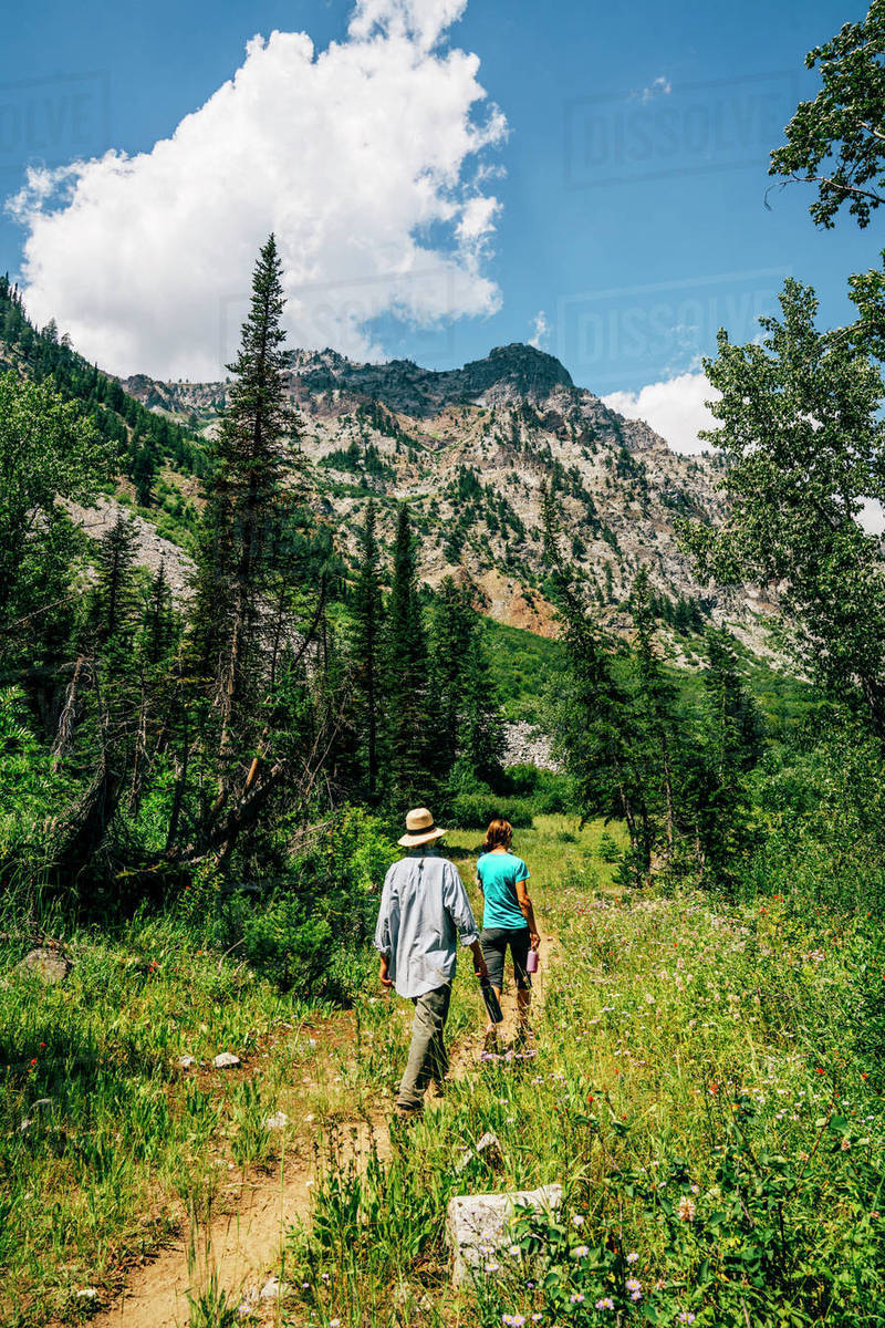 Caucasian couple hiking on path in mountains - Stock Photo - Dissolve