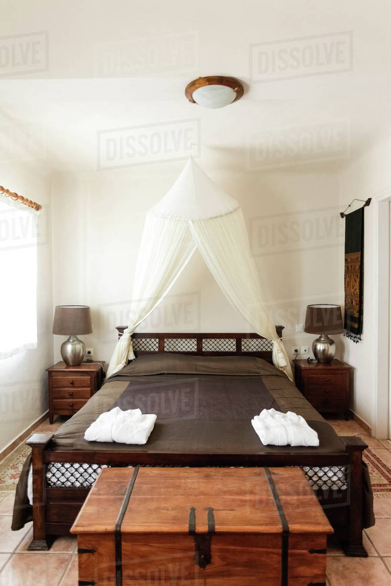 Chest near wooden bed in bedroom - Royalty-free Stock Photo | Dissolve