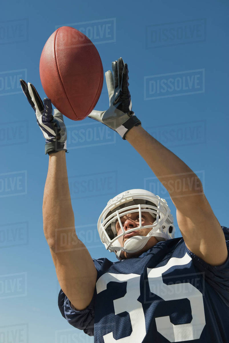Hispanic male football player catching ball - Royalty-free Stock Photo ...