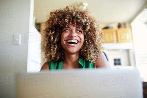 Laughing woman using laptop - Stock Photo - Dissolve