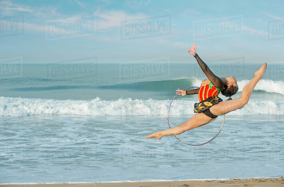 Gymnast jumping with hoop on beach - Stock Photo - Dissolve