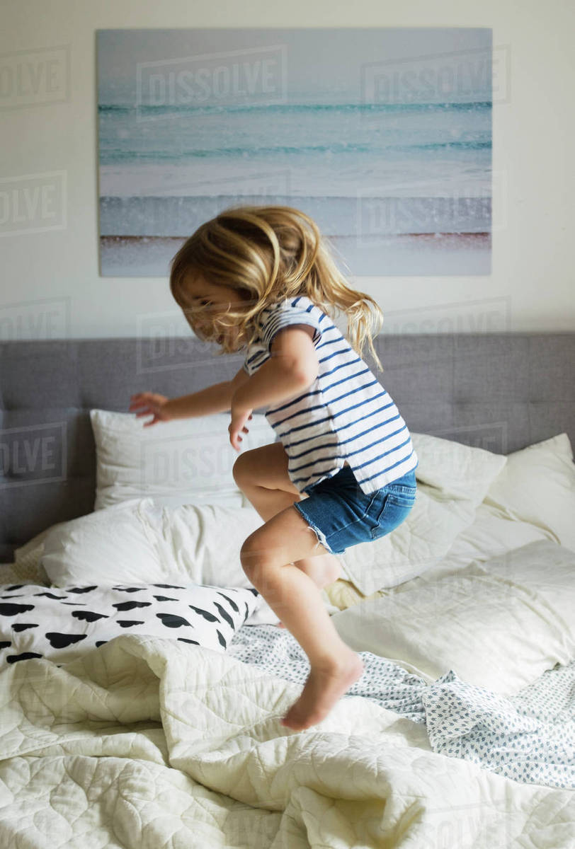 Girl jumping on bed - Royalty-free Stock Photo | Dissolve
