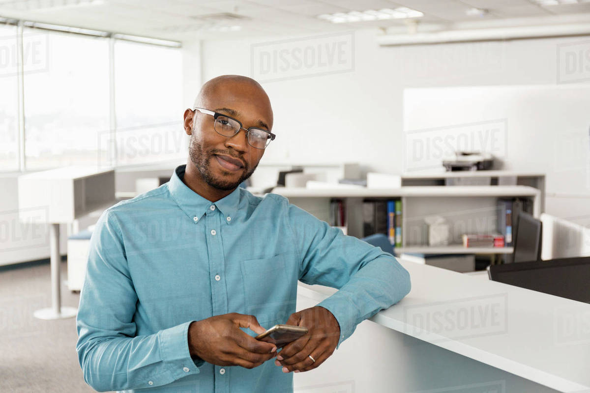 Smiling African American man texting on cell phone in office - Royalty ...