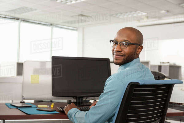 Smiling African American man using computer in office - Royalty-free ...