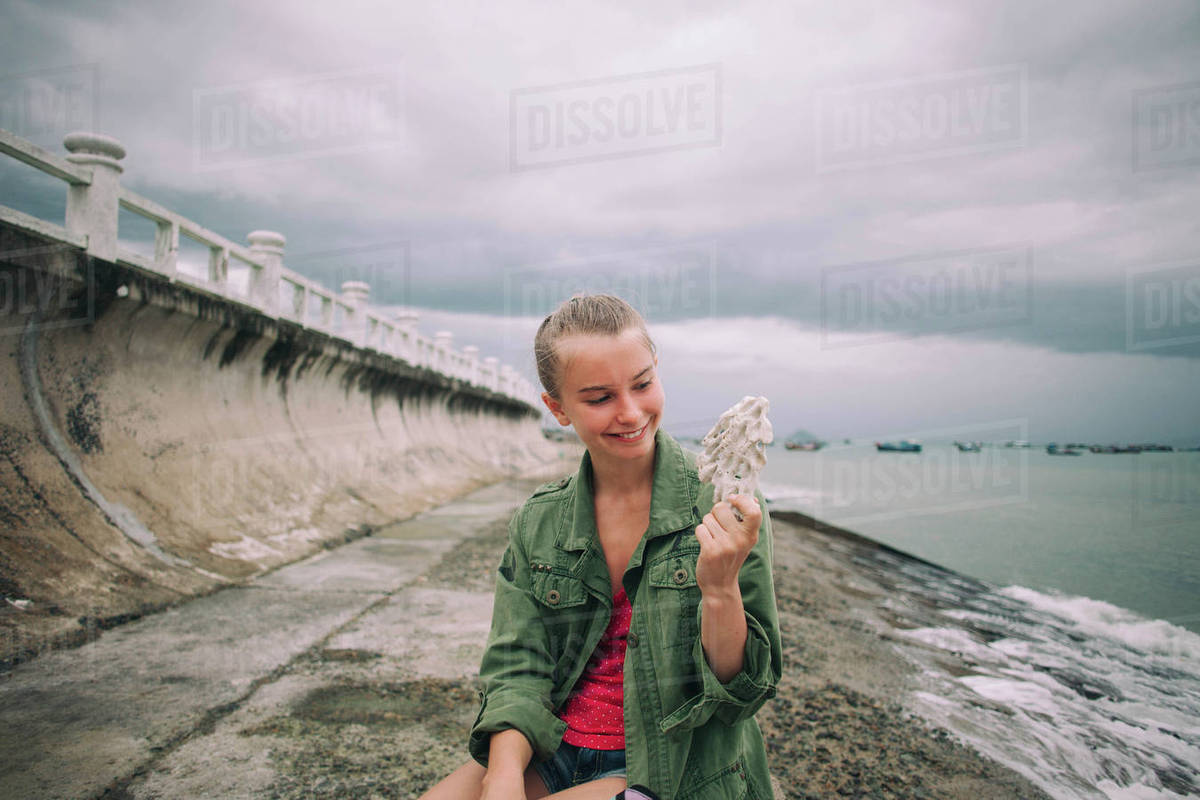 Woman holding shell at beach - Royalty-free Stock Photo | Dissolve