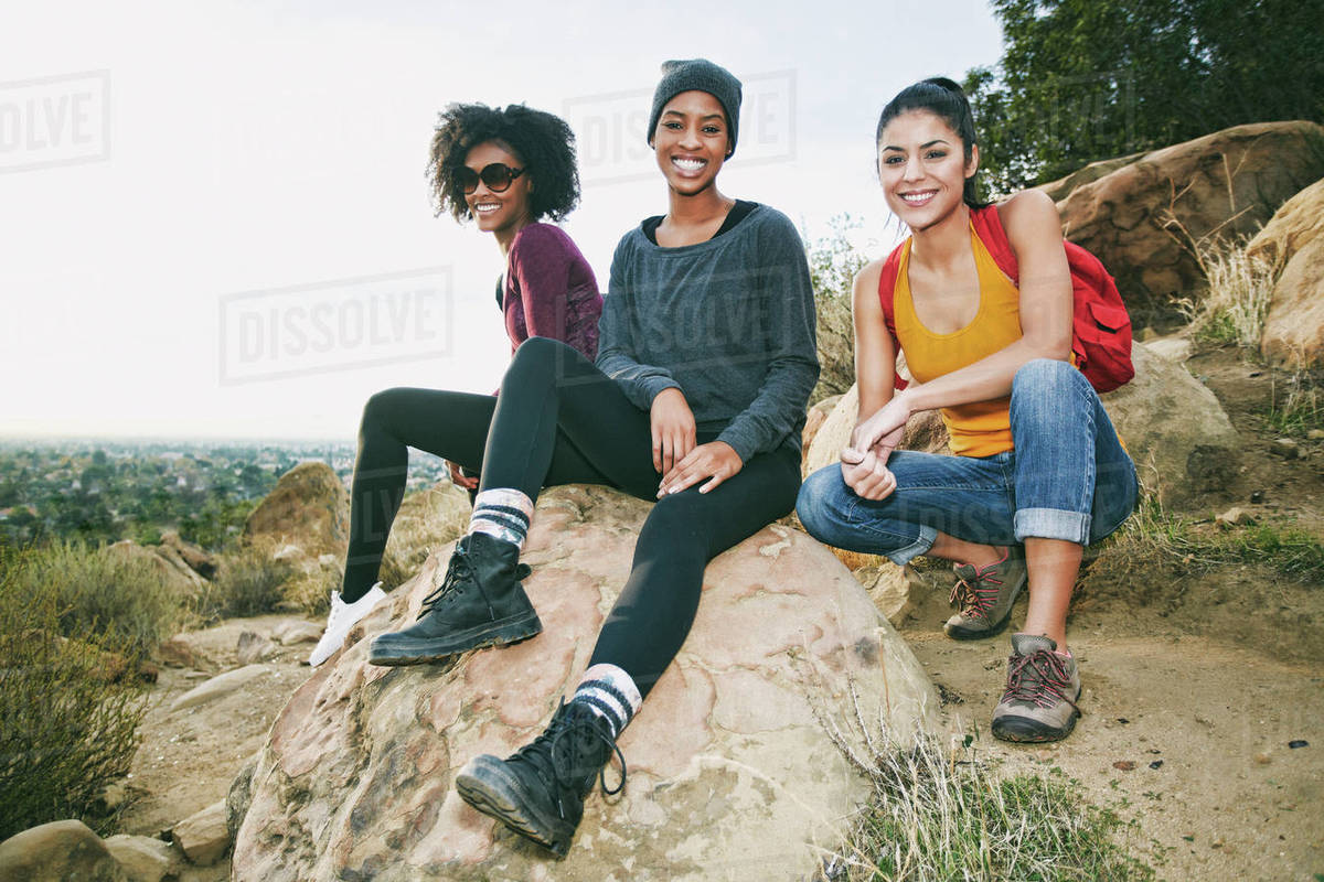 Portrait of smiling women sitting on rock - Royalty-free Stock Photo ...