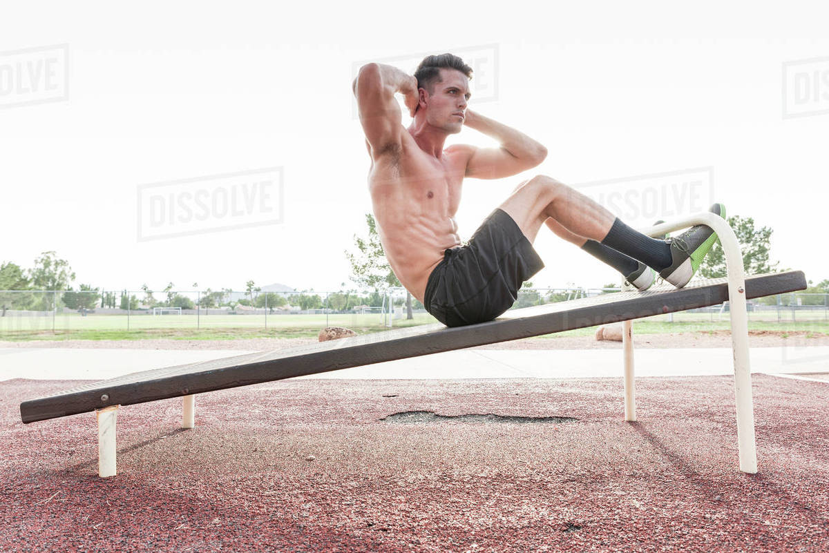 Caucasian man doing sit-ups outdoors - Stock Photo - Dissolve