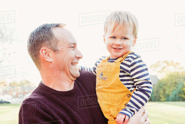 Laughing Caucasian father holding son - Stock Photo - Dissolve