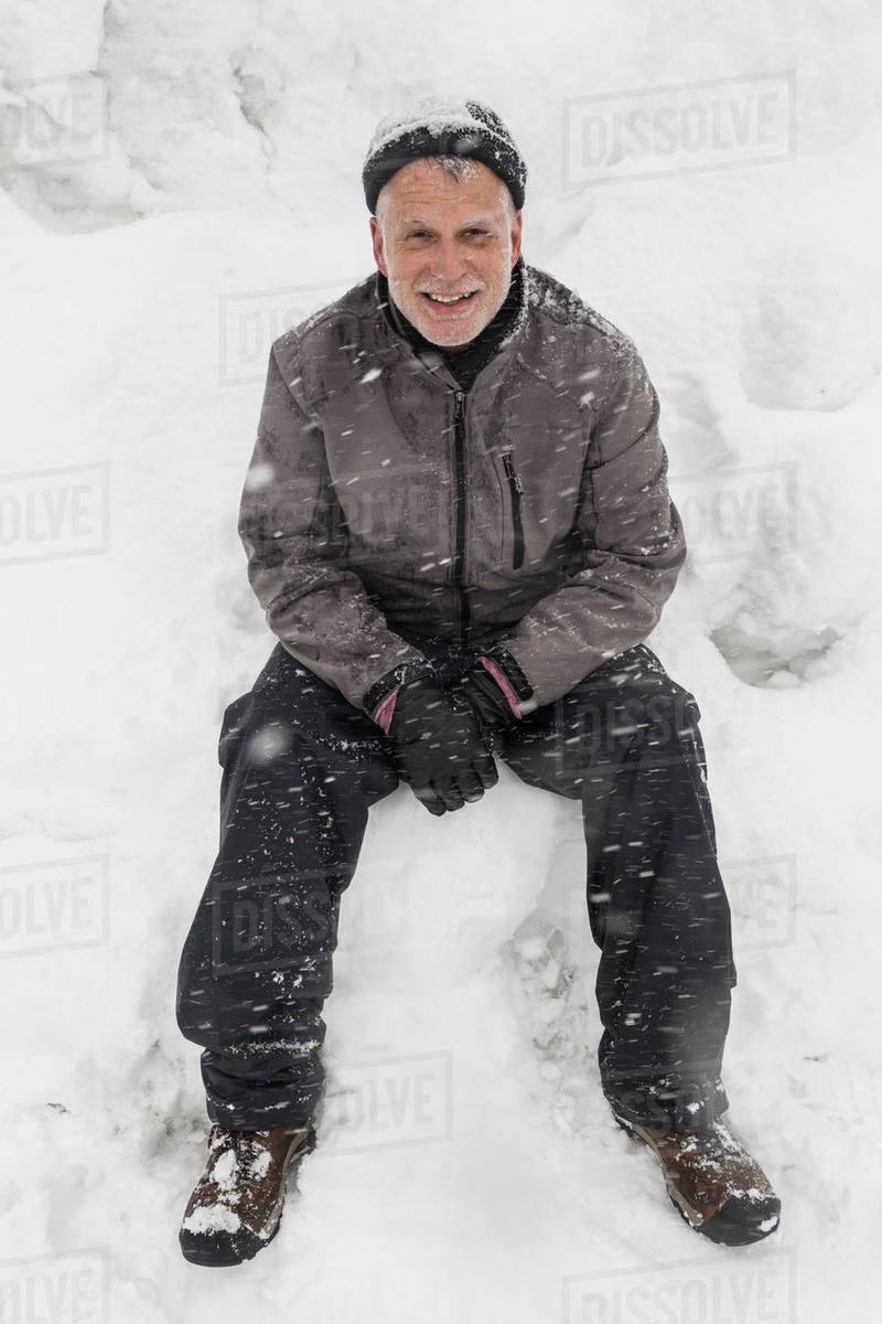 Smiling Caucasian man sitting on pile of snow - Royalty-free Stock ...