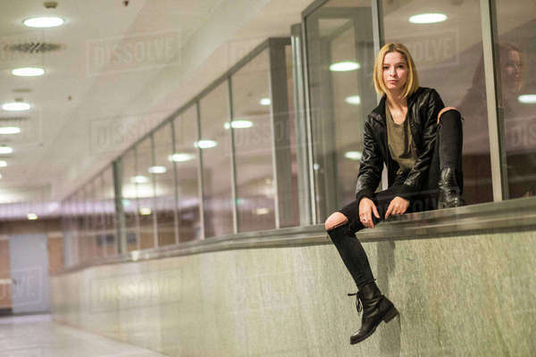 Caucasian woman sitting on ledge of window in corridor - Stock Photo ...