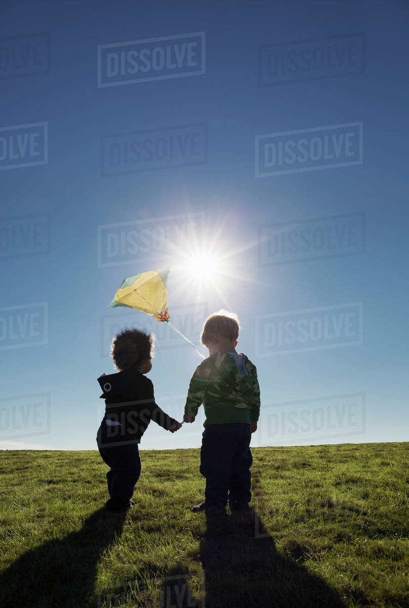 Boys watching kite flying against blue sky - Royalty-free Stock Photo ...