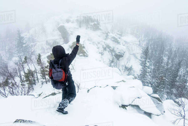 Caucasian hiker waving on snow covered mountain - Stock Photo - Dissolve