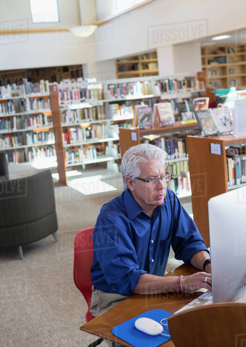 Serious Hispanic man using computer in library - Royalty-free Stock ...