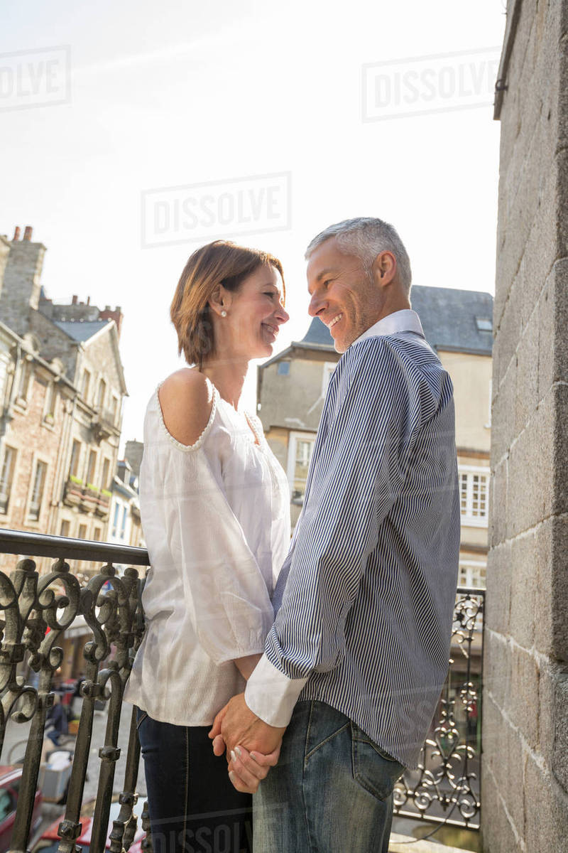 Caucasian couple holding hands on balcony in city - Stock Photo - Dissolve