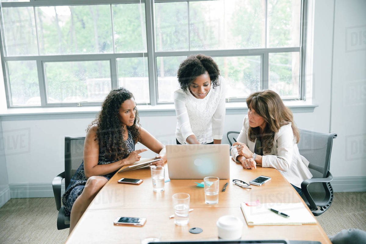 Businesswomen using laptop in meeting - Stock Photo - Dissolve