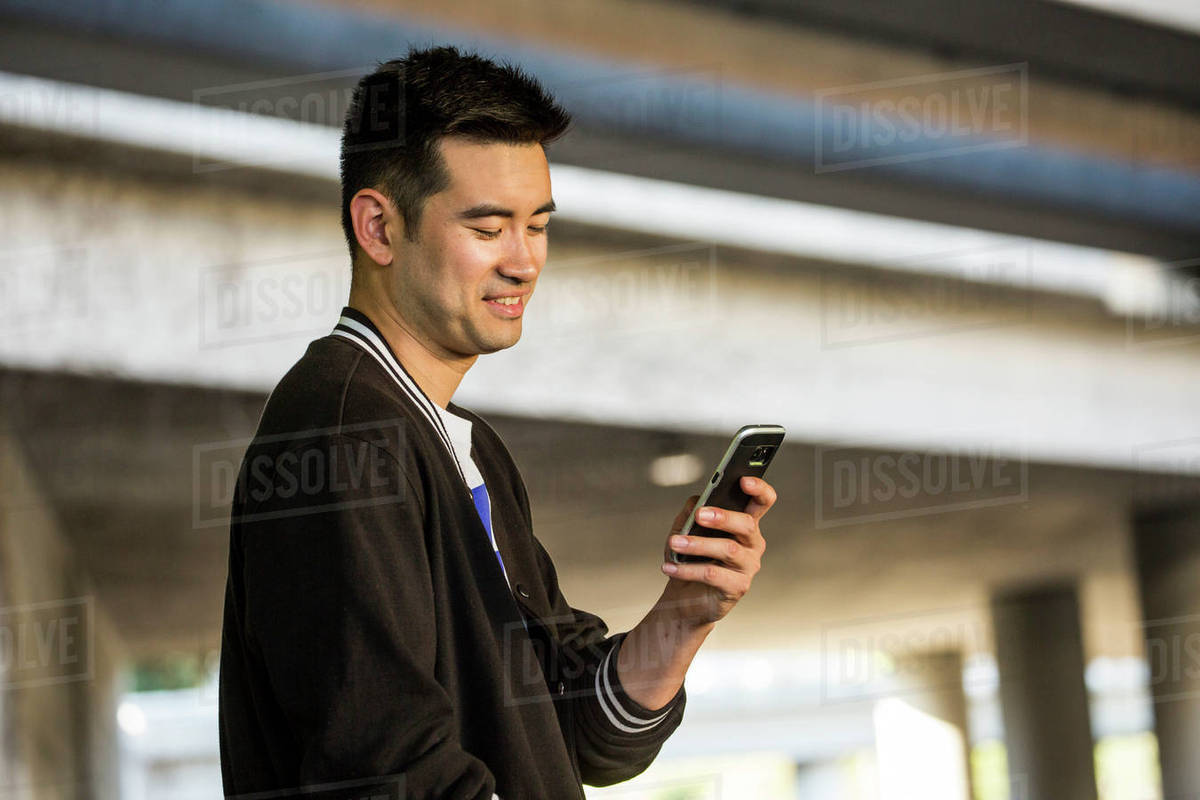 Smiling Chinese man texting on cell phone - Royalty-free Stock Photo ...