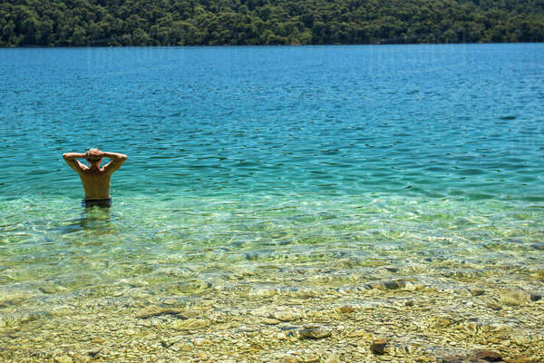 Caucasian man wading in water - Stock Photo - Dissolve