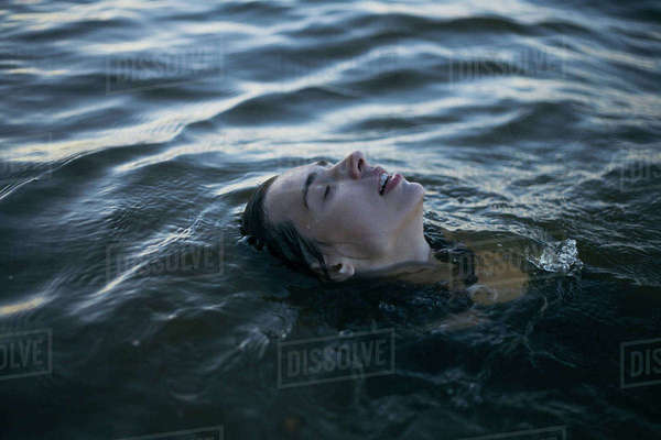 Caucasian woman floating in ocean with eyes closed - Stock Photo - Dissolve
