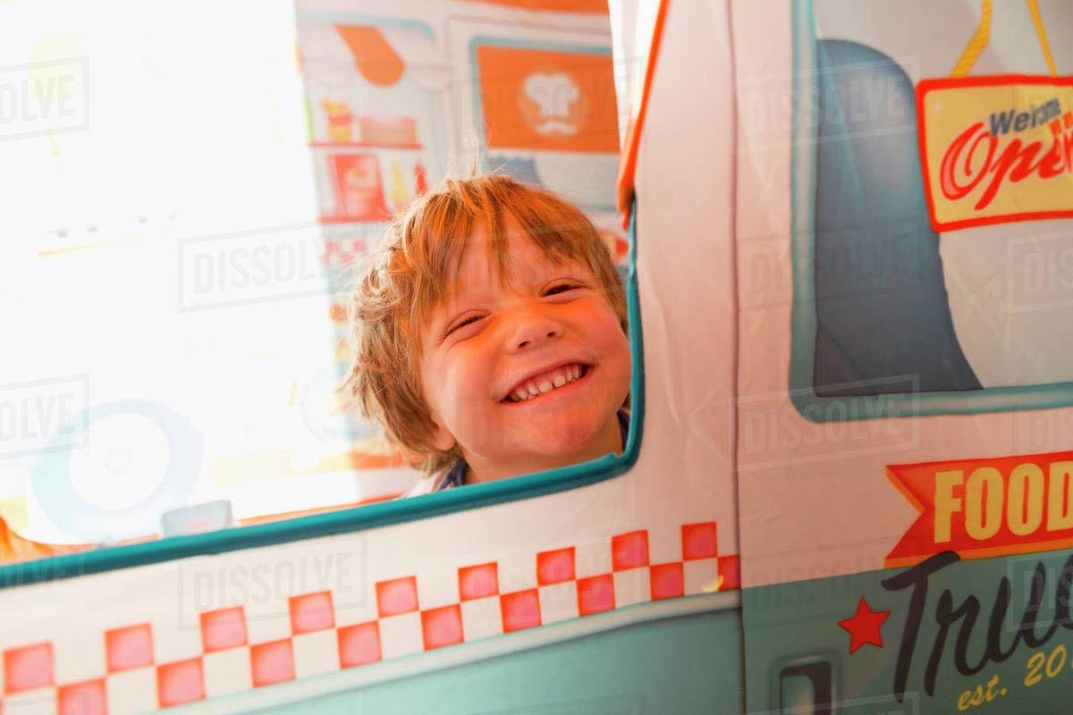 Portrait of smiling Caucasian boy in window - Stock Photo - Dissolve