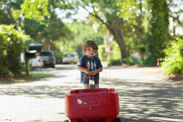 Caucasian boy pulling red wagon in street - Royalty-free Stock Photo ...