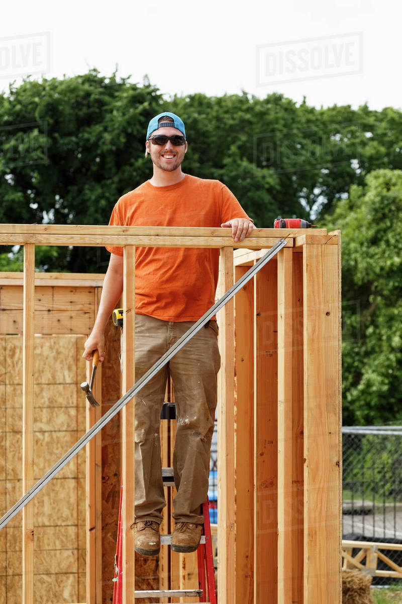 Portrait of Caucasian man standing on ladder at construction site ...