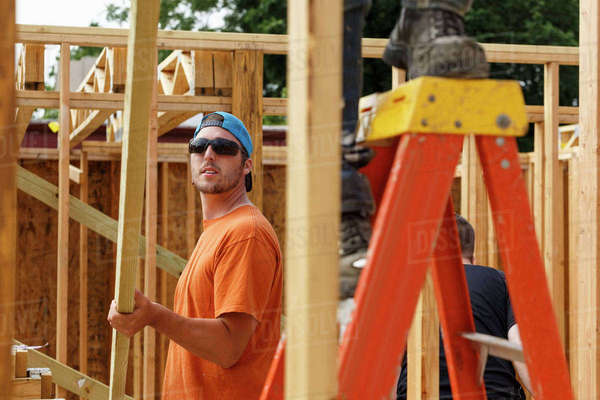 Caucasian man lifting lumber at construction site - Royalty-free Stock ...